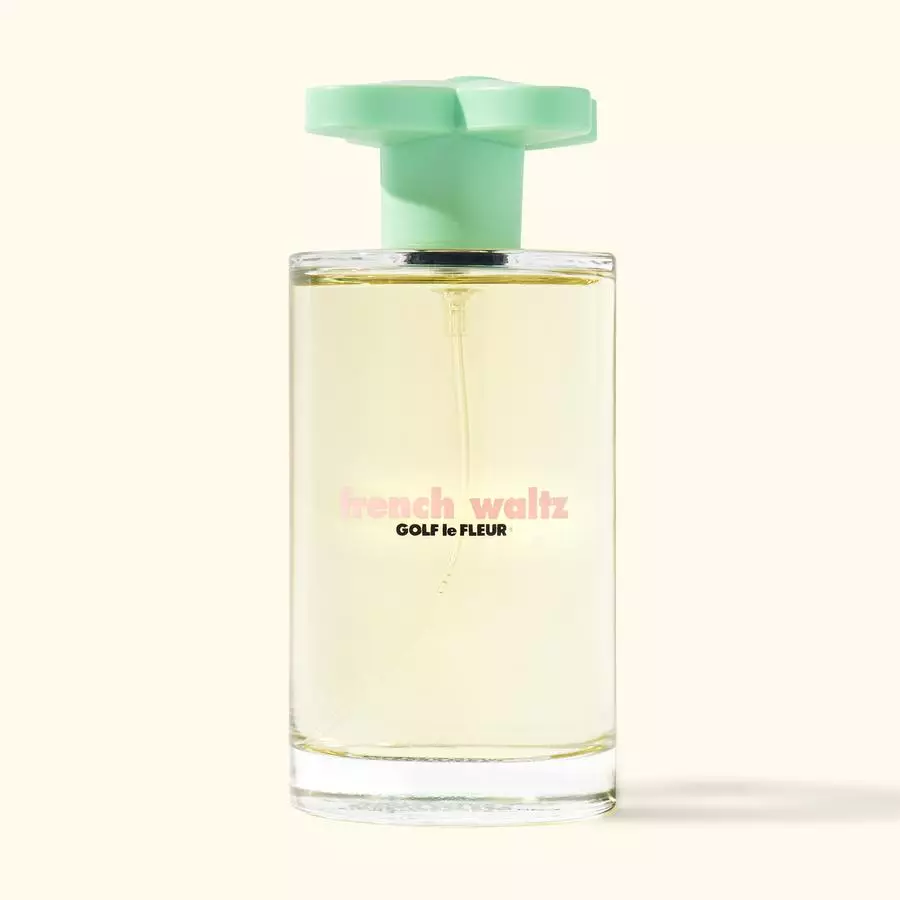 Sticla cu parfum de vals francez Golf Le Fleur. Este într-o sticlă cilindrică transparentă cu un vârf de floare verde.