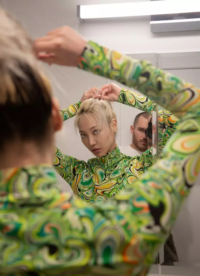 soo joo park where the heart is waring green pattern dress looking in mirror with hands up fixing hair