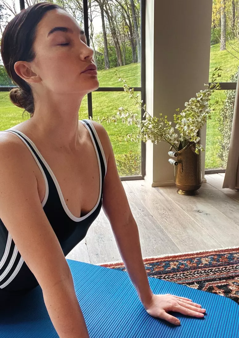 larawan ng modelong si Lily Aldridge sa bahay na nakasuot ng workout outfit, tight bun, at walang makeup