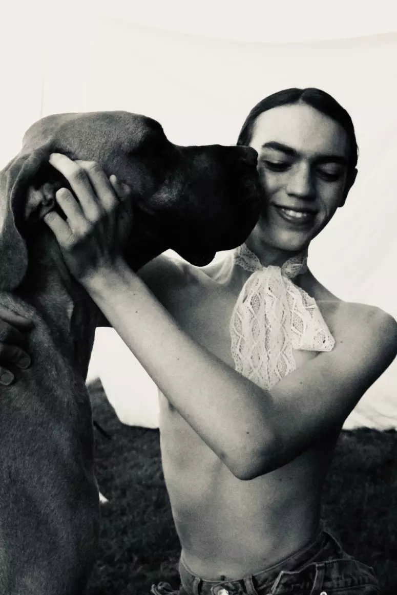 Larawan ng modelong si Bryce Anderson sa bahay na nakasuot ng lace bow at maong, kasama ang kanyang Great Dane Bear.