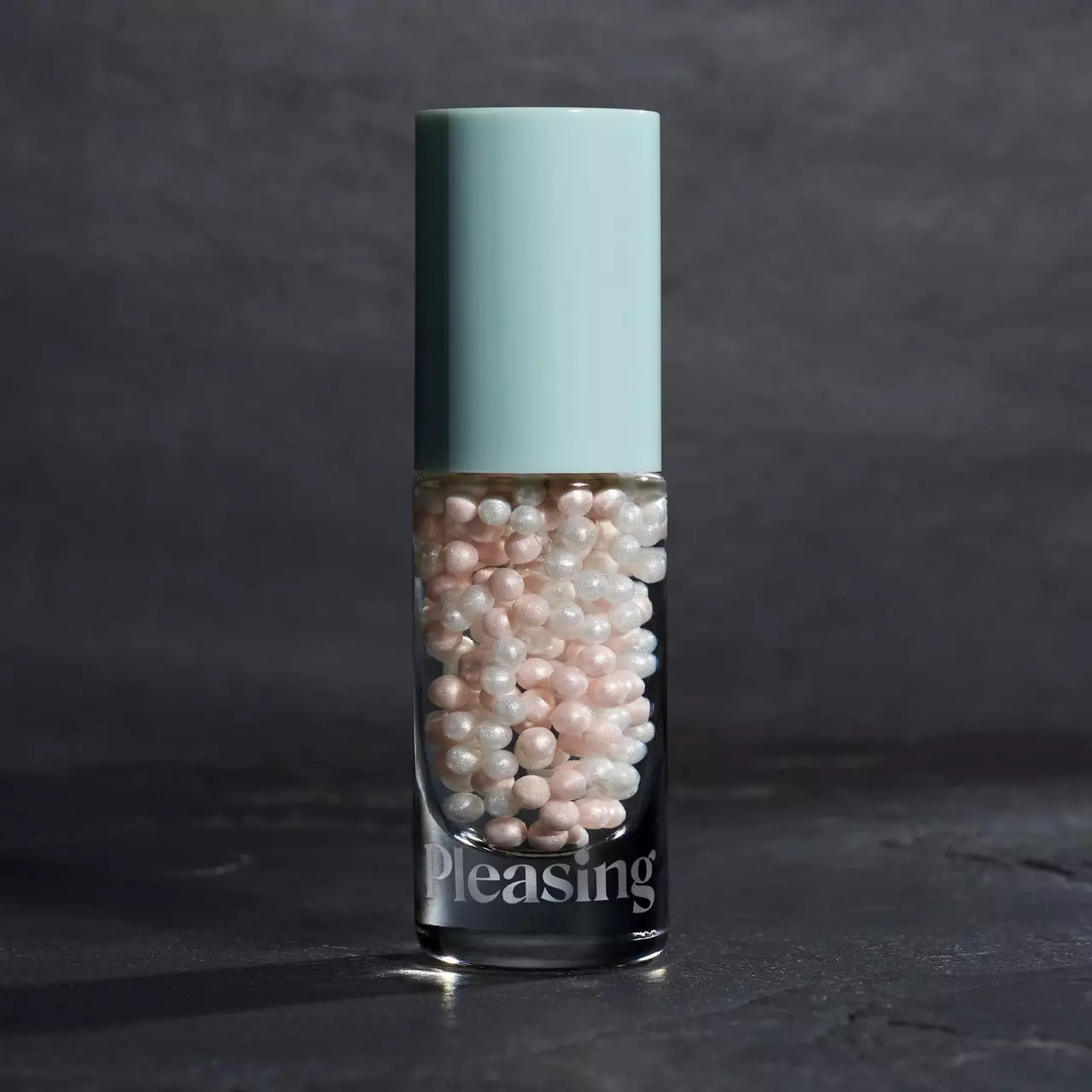 Pleasing The Pearlescent Illuminating Serum på sort baggrund