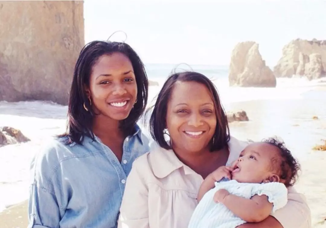 Shanelle Drakeford och hennes mamma håller en bebis på en strand