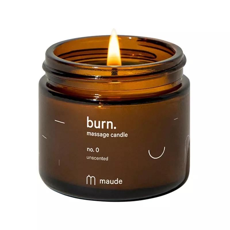 The Maude Burn No. 0 Massage Candle a cikin wani launin ruwan kasa a kan wani farin bango